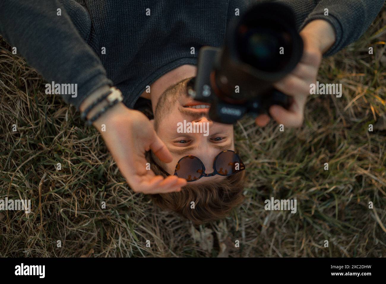 Man lies on the grass with a camera, watching pictures Stock Photo - Alamy