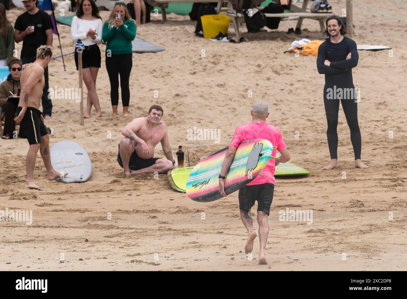 A surfer carrying his surfboard running out of the sea after competing ...