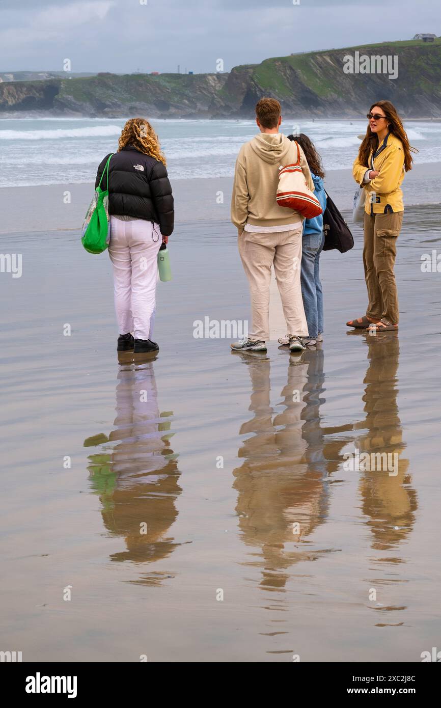 A group of young holidaymakers visitors tourists standing at low tide ...
