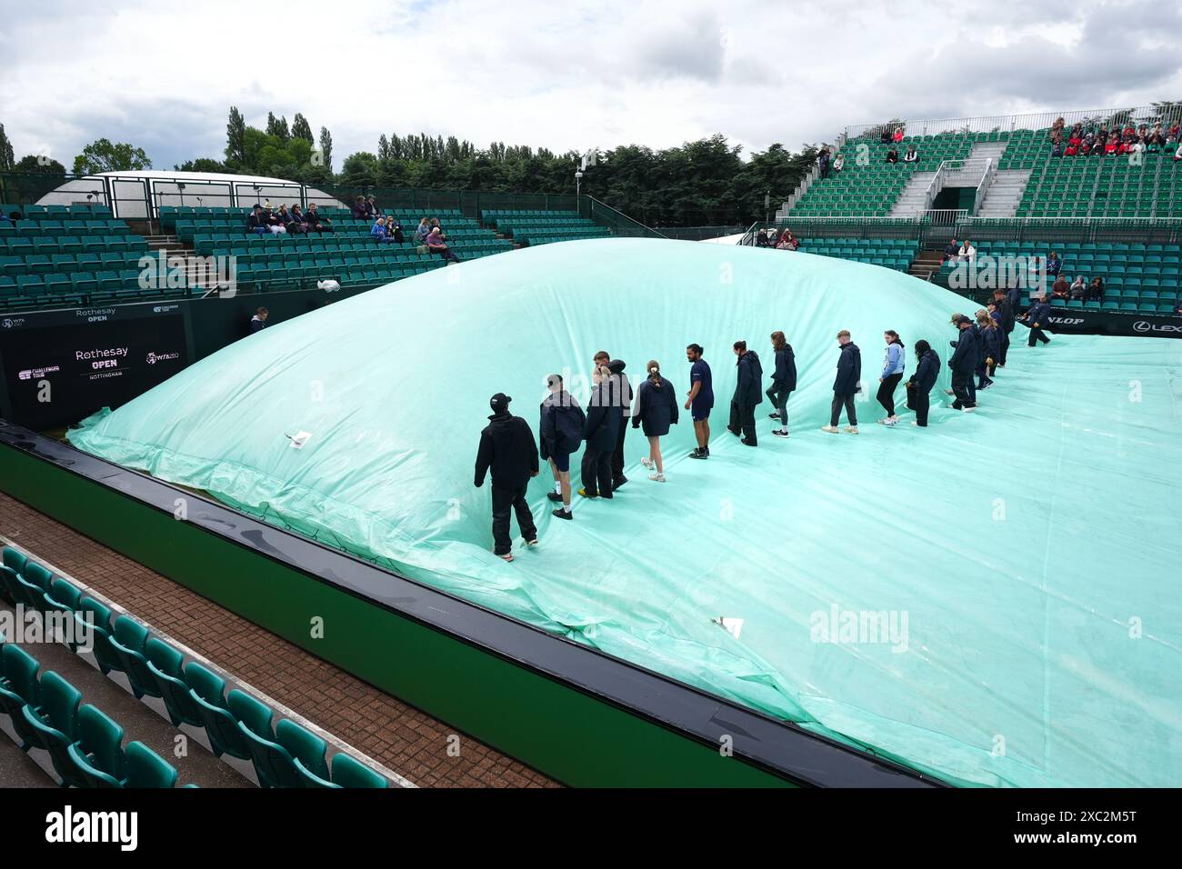 The ground staff cover the court with a rain cover on day five of the ...