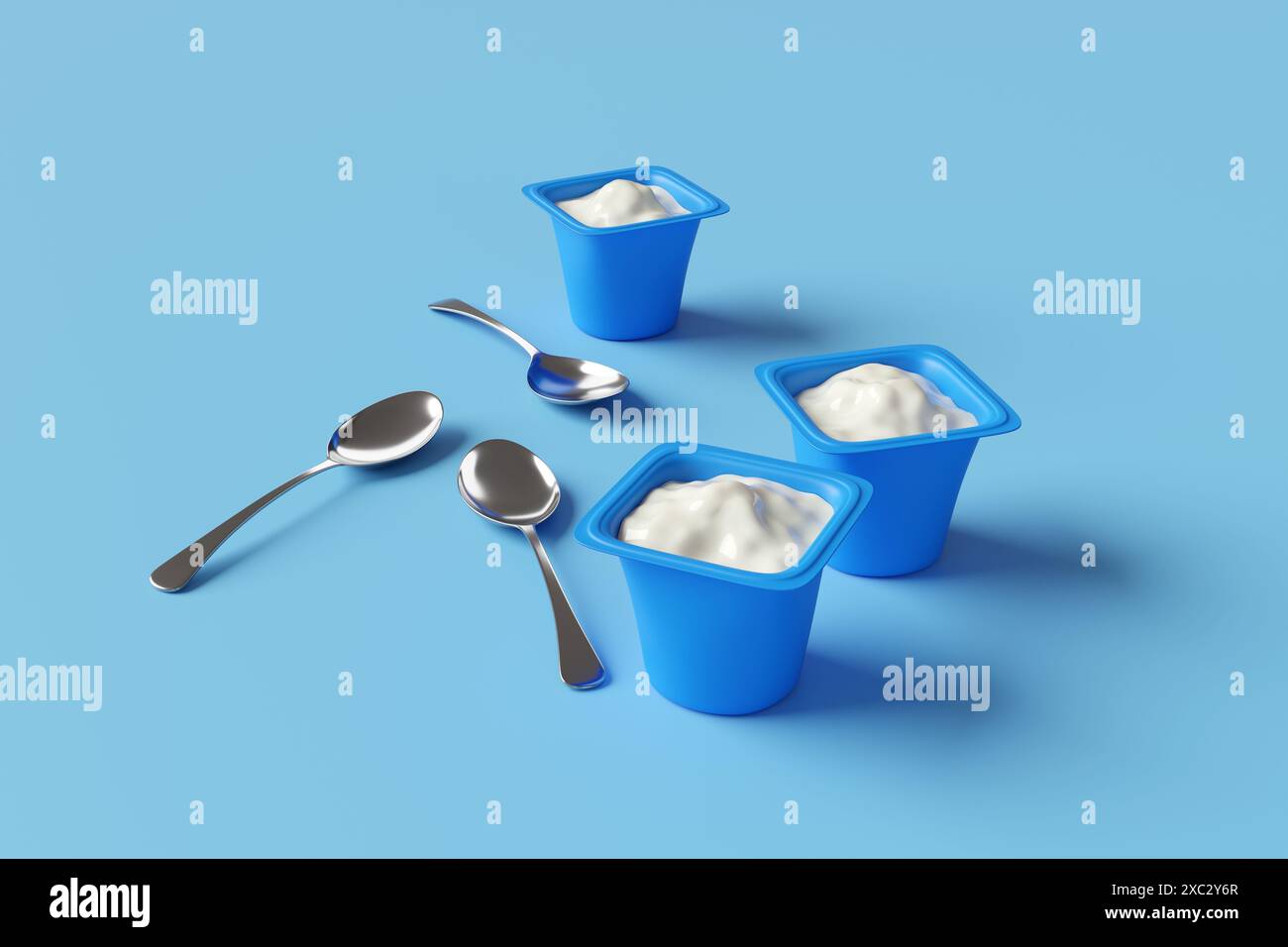 Yogurt in blue cup-shape containers and silver spoons on blue ...