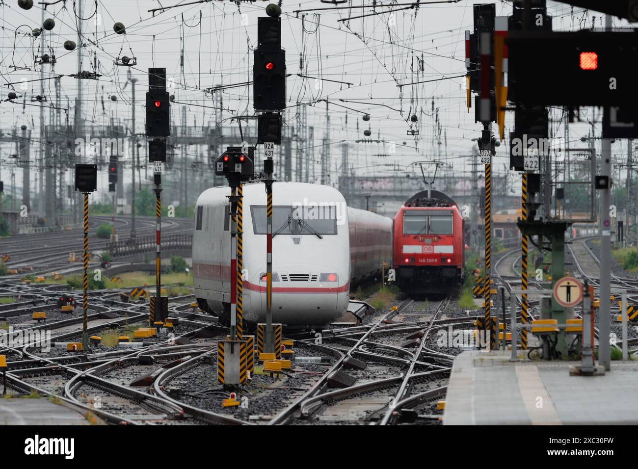 Two trains stand on railway tracks surrounded by signals and overhead ...