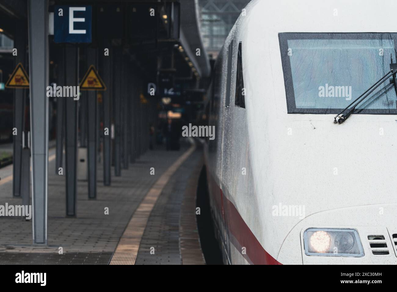 German high-speed train at a modern railway station platform on a rainy ...