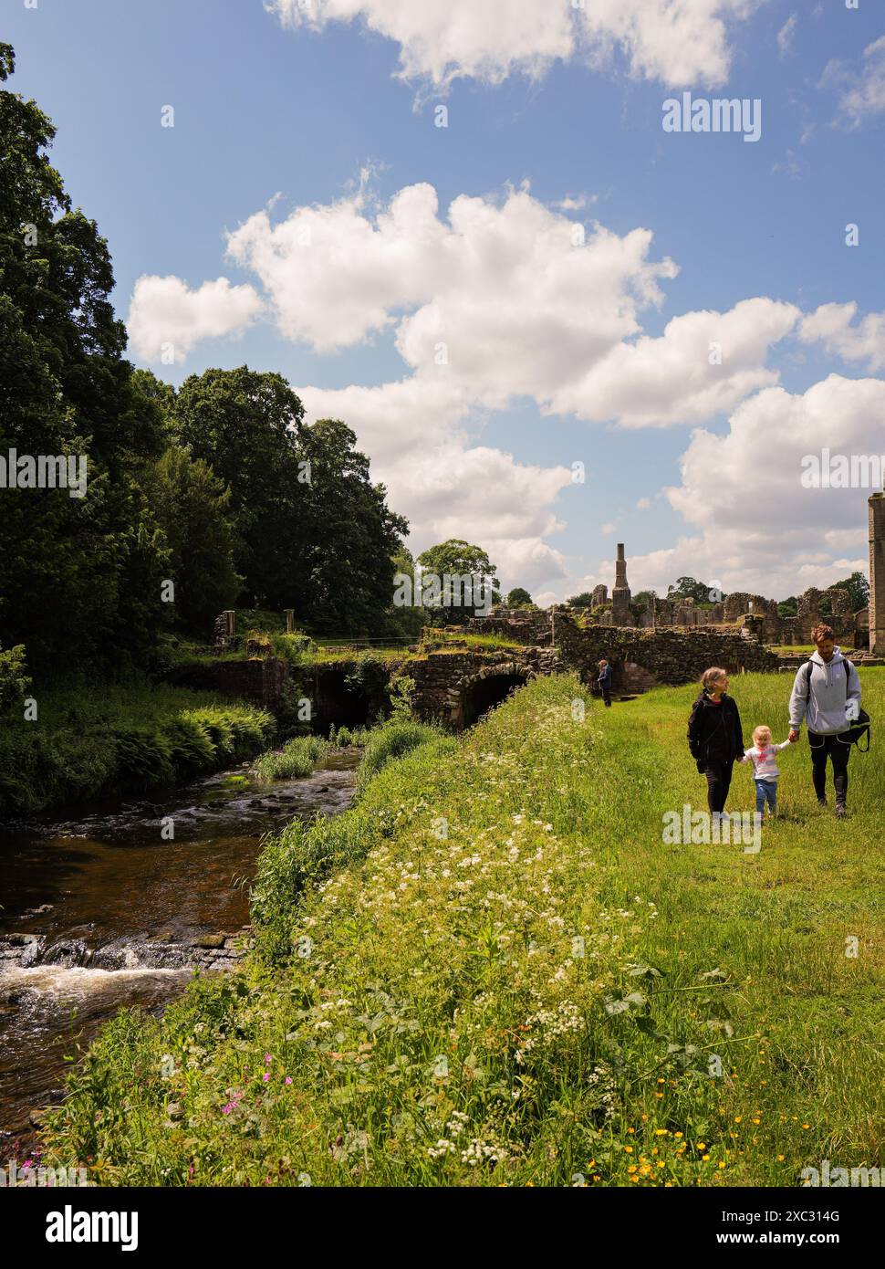 Fountains Abbey in the background with a young family unit in the ...