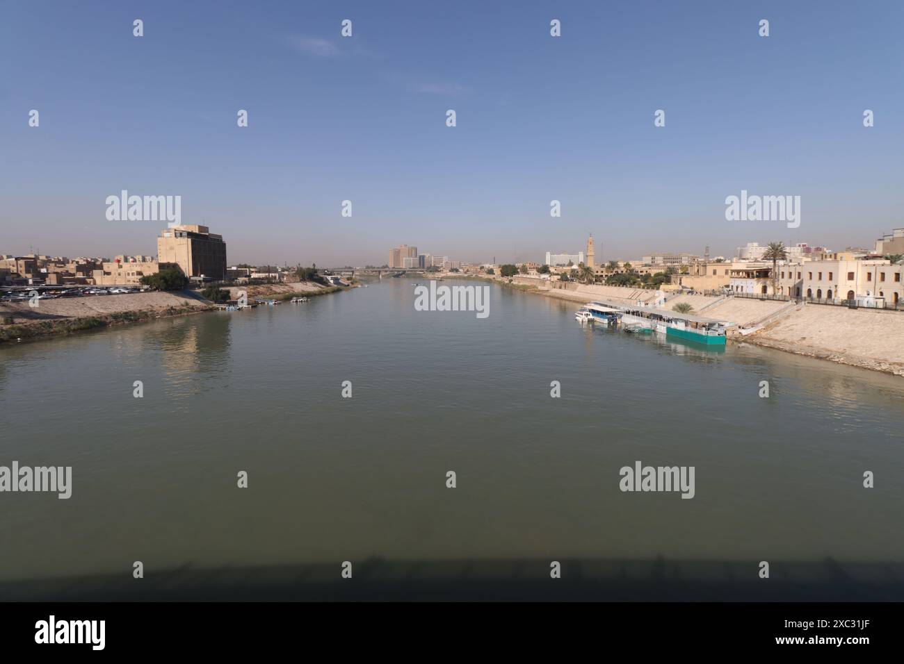 A serene view of the Tigris River with buildings and boats on a sunny ...