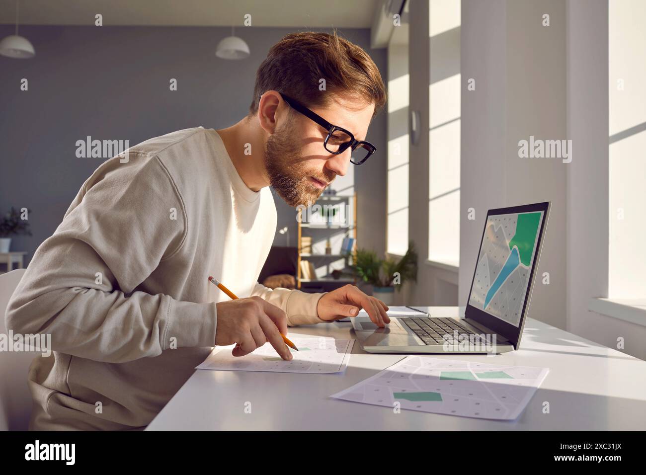 Professional cartographer working with printed cadastral map at table ...