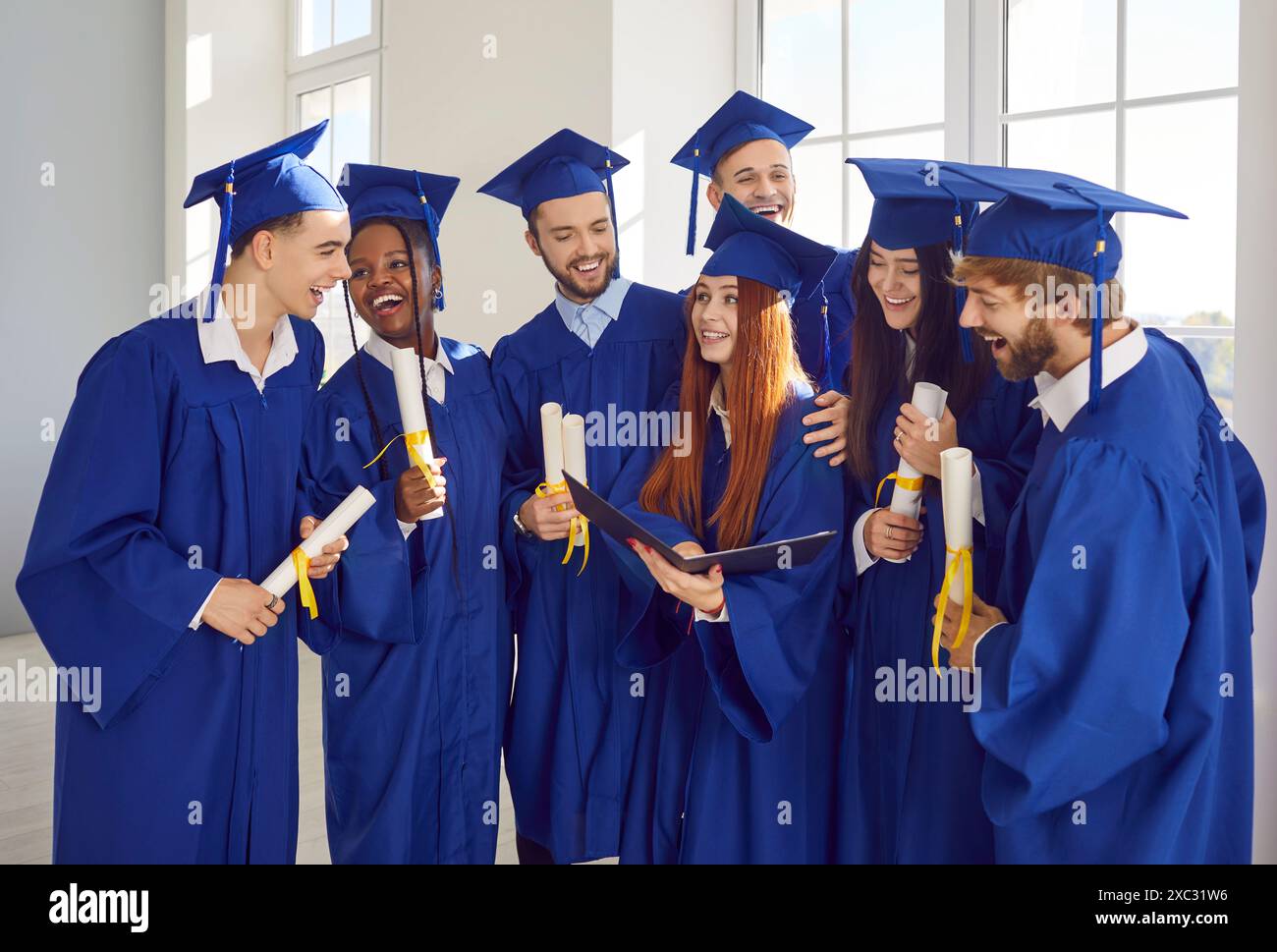 Portrait of happy diverse graduates talking together and holding ...