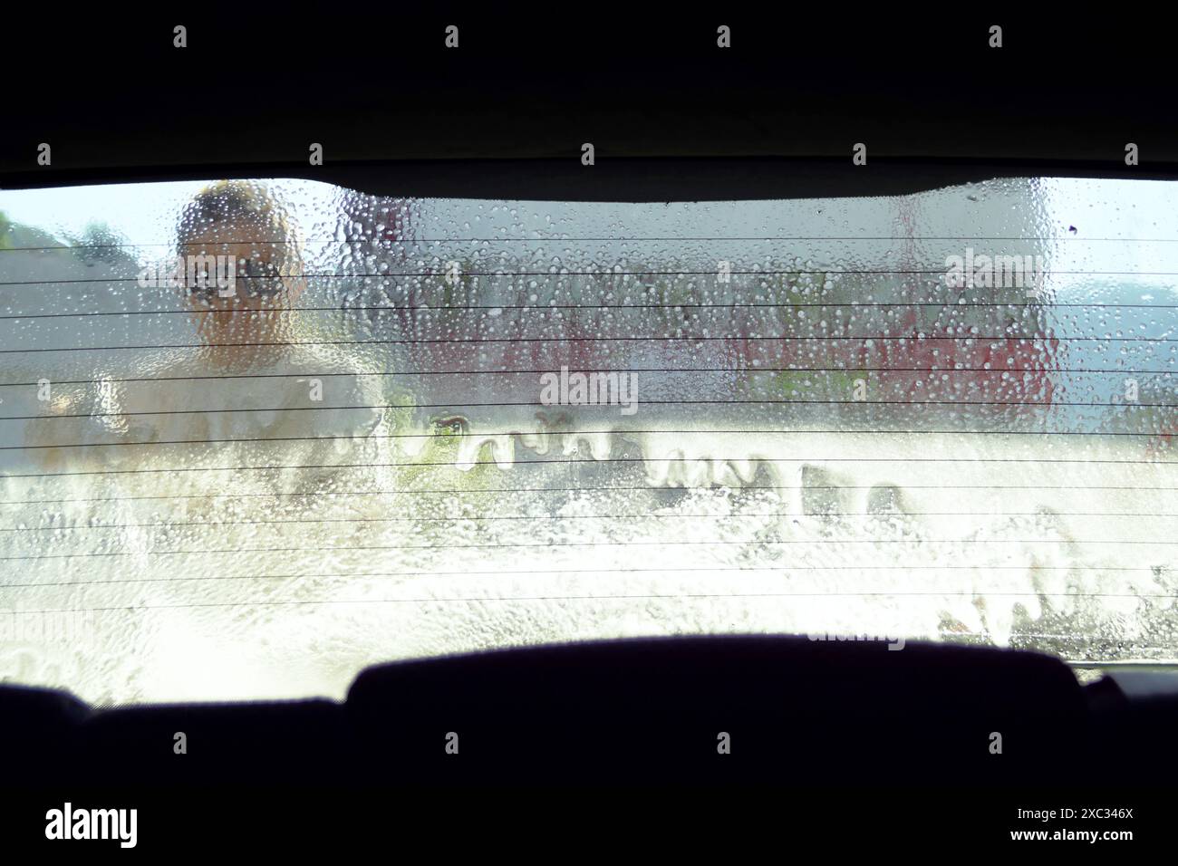 A view from inside a car of a man washing the rear window. Close-up ...
