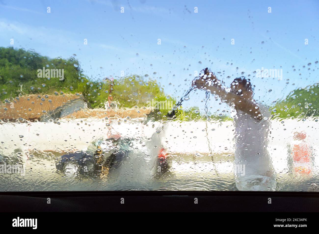Cleaning windshield using a stream of water from a washing gun - a man ...
