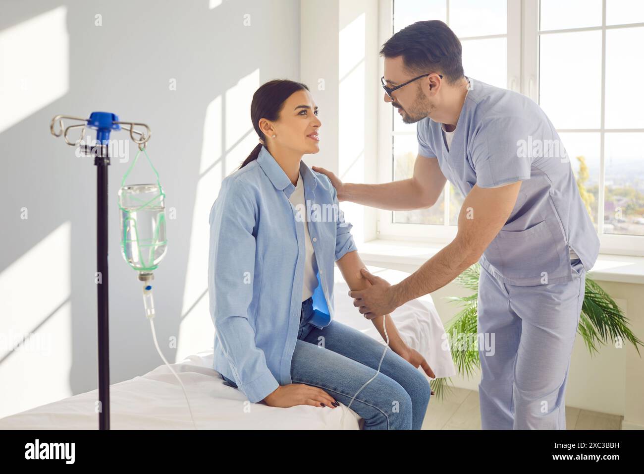 Female patient sitting on couch in medical clinic receiving IV drip ...