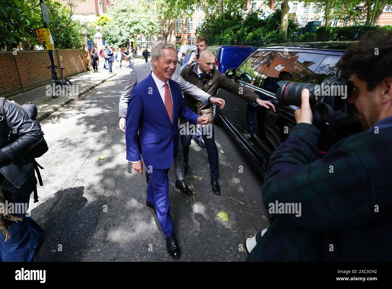 A member of Reform UK leader Nigel Farage's (centre) security detail ...