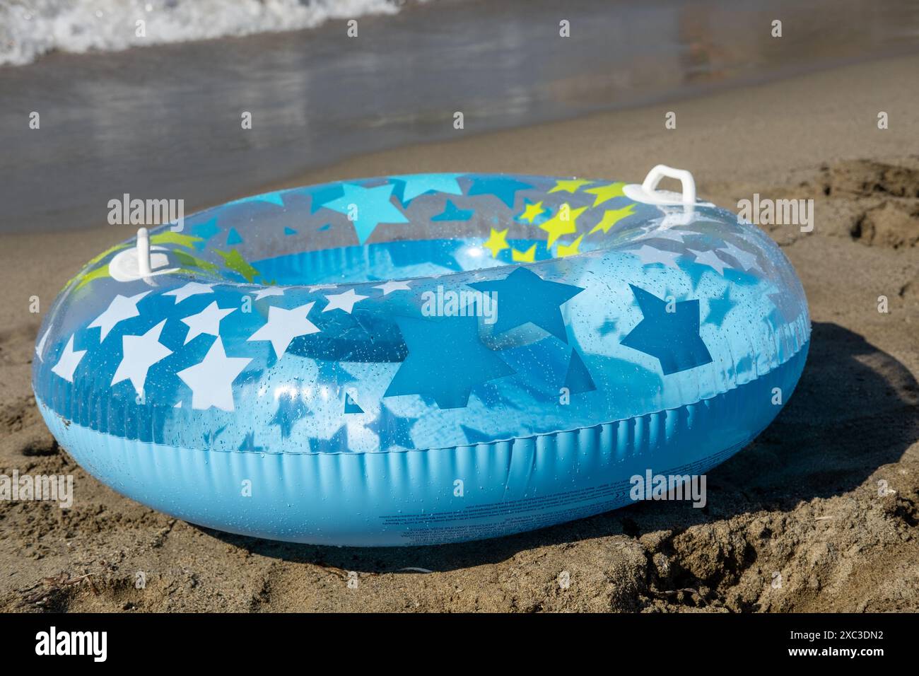 Beach scene with an inflatable rubber ring on the sand as the waves ...