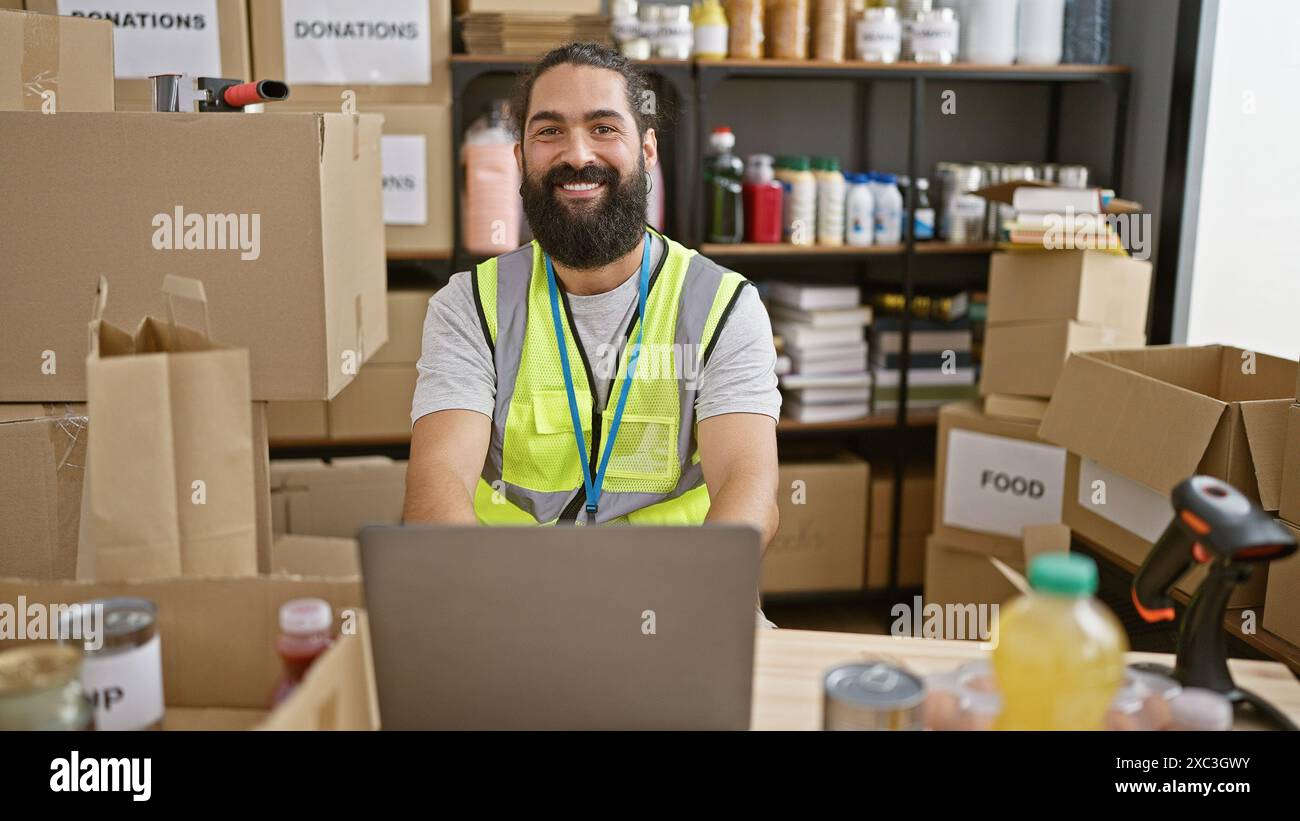 Handsome bearded man smiling at workplace with laptop, donation boxes ...
