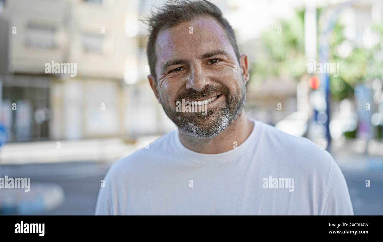 A smiling hispanic middle-aged man with grey hair posing outdoors on an ...