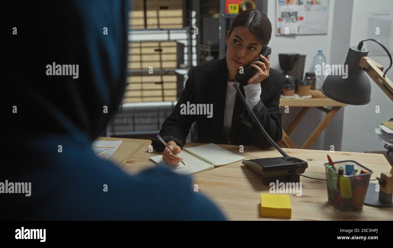 A female investigator attentively listens on a call, taking notes in an ...