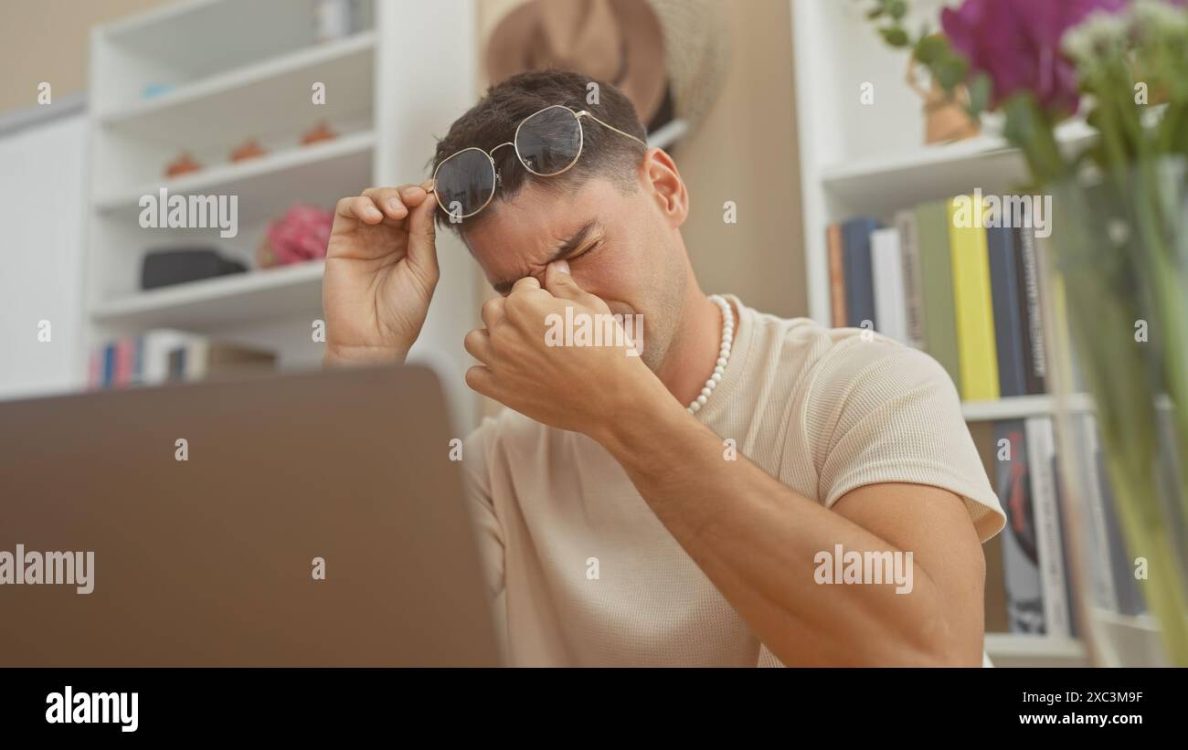Stressed young hispanic man pinching the bridge of his nose at home ...