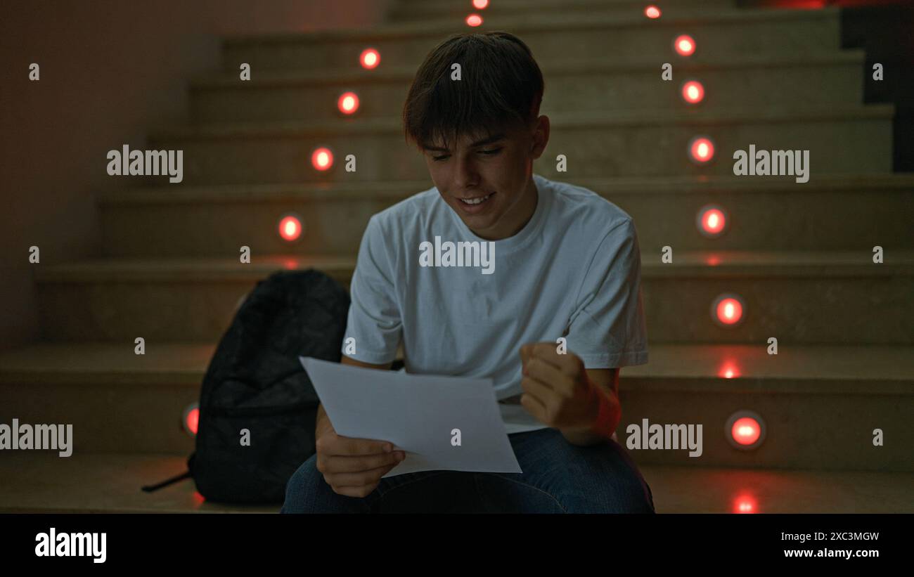 Caucasian teenage boy studying paper on university campus steps ...
