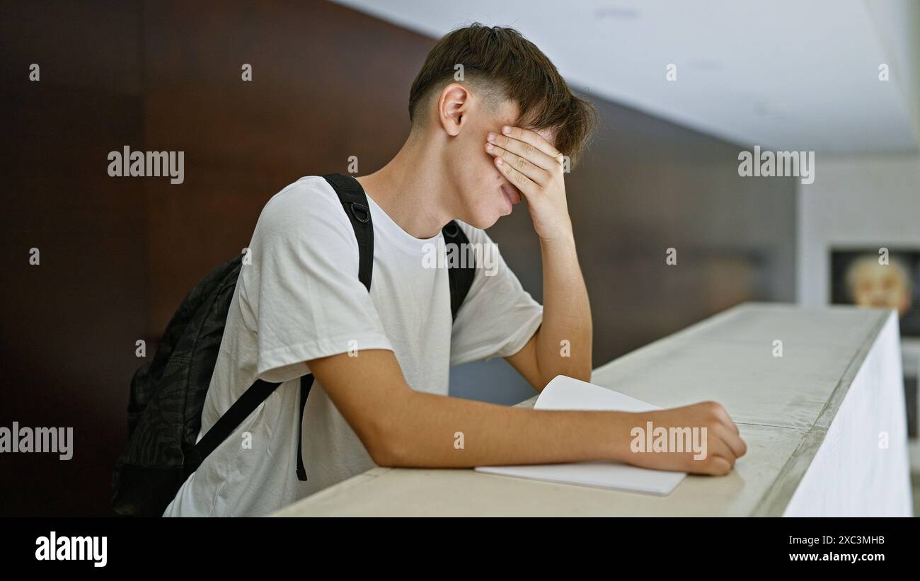 Stressed teenage boy with backpack touching forehead in a school ...