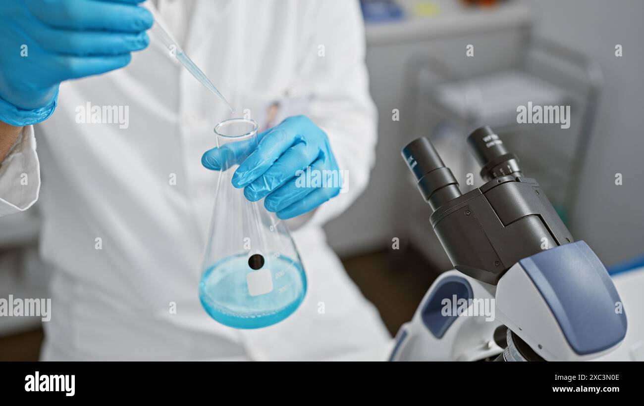 A man conducting an experiment in a laboratory wearing gloves with a ...