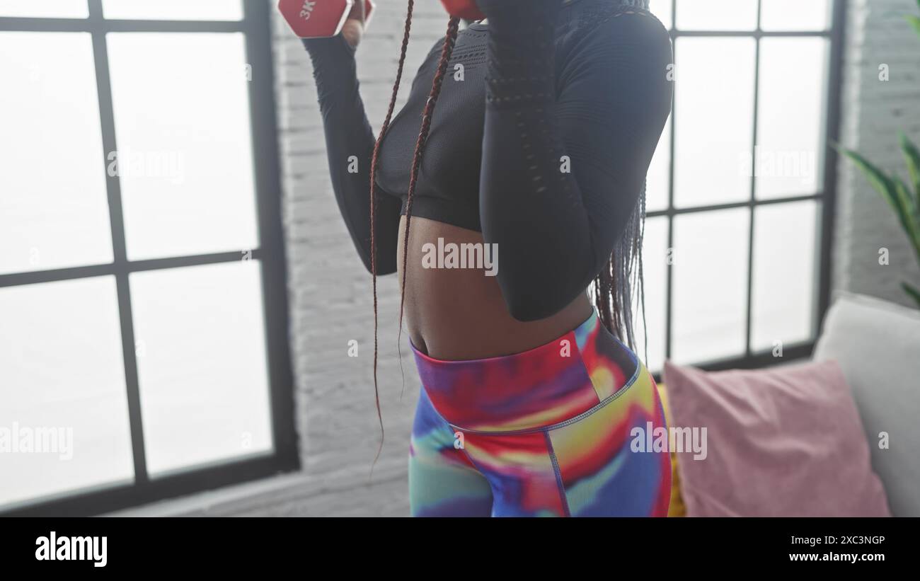 An african american woman with braids exercises indoors, showcasing a ...