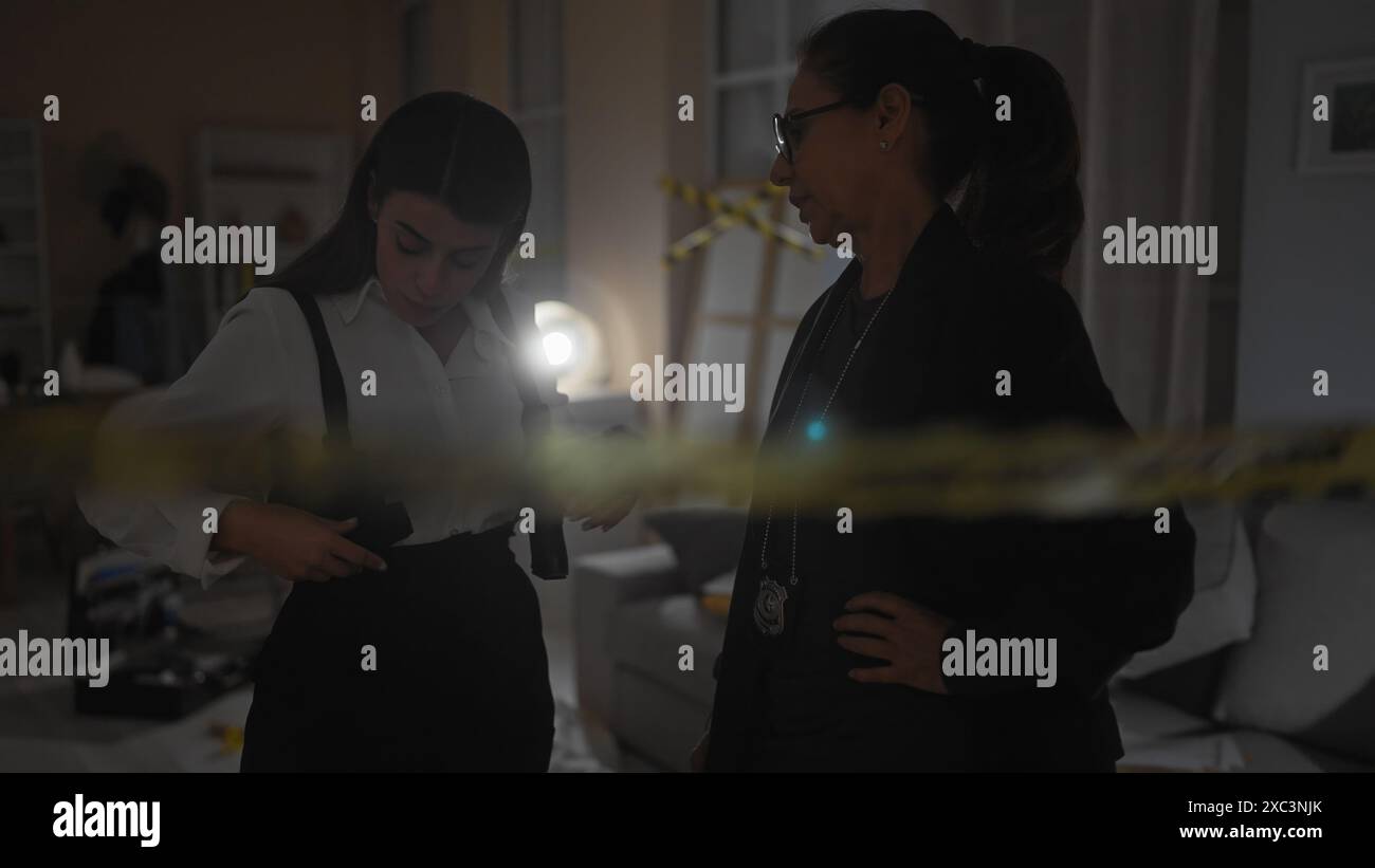 Two women detectives analyze evidence at an indoor crime scene, with ...