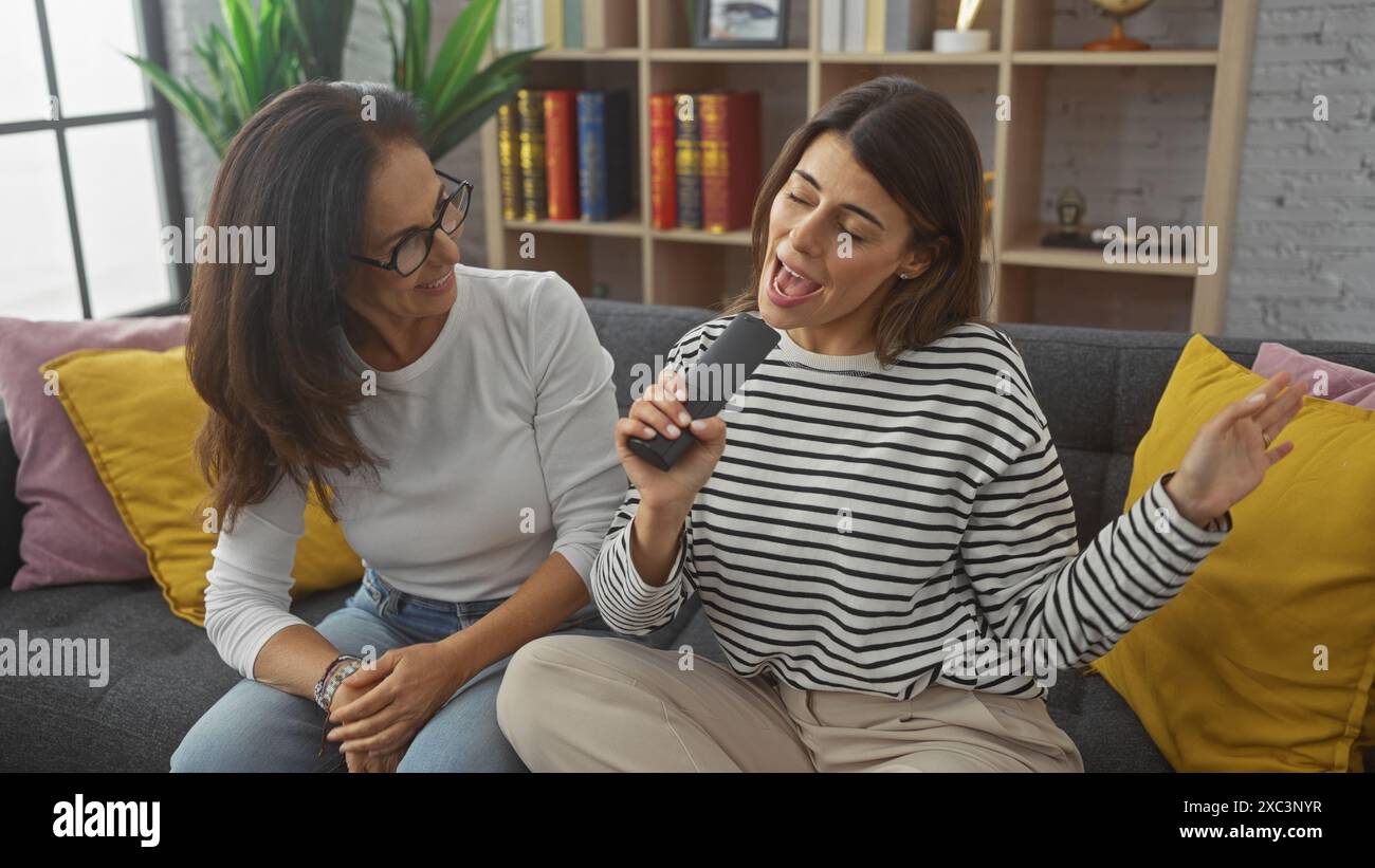 Mother and daughter bonding on a couch, singing into remote control ...