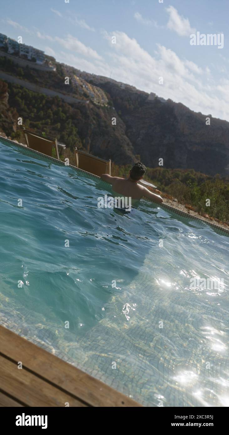 Man relaxing in an outdoor infinity pool overlooking a stunning ...