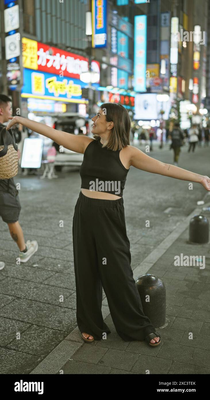 Joyful brunette hispanic woman embracing tokyo's night lights, open ...