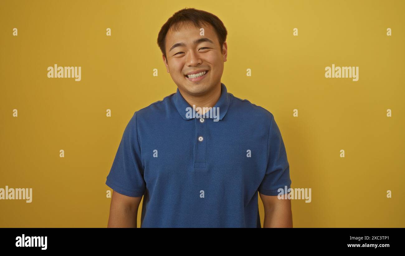A handsome young chinese man is smiling warmly, wearing a blue polo ...