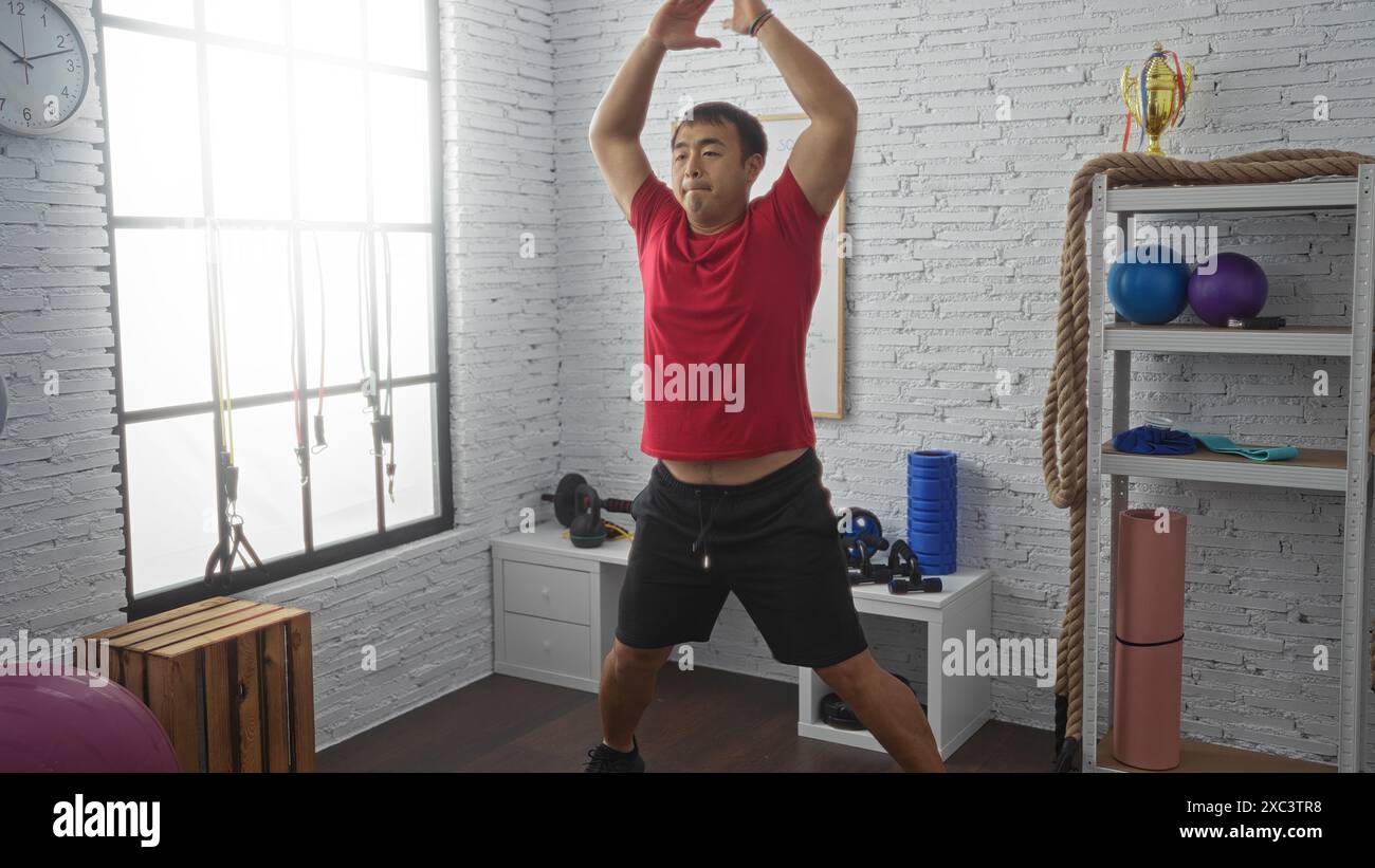 Young chinese man exercising in a gymnasium filled with equipment like ...