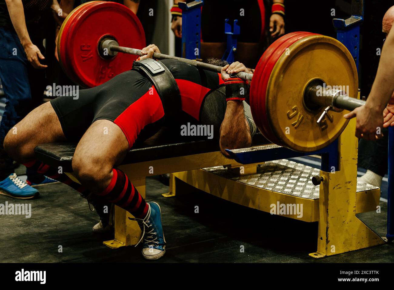 athlete perform bench press surrounded by assistants at powerlifting ...