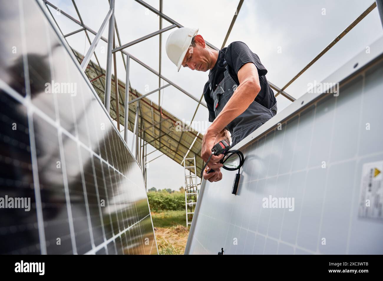 Serious man solar installer assembling photovoltaic solar panel system ...