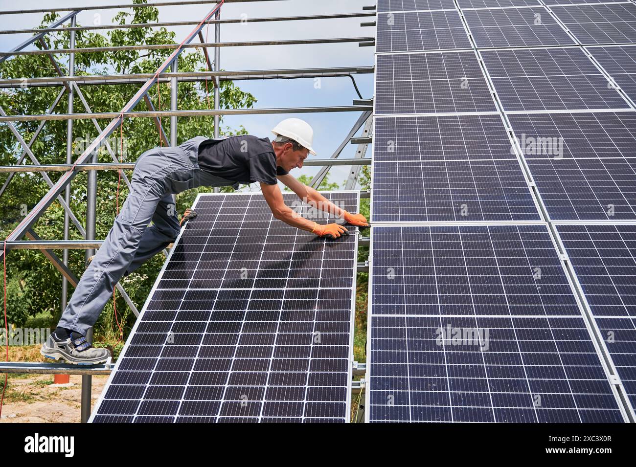 Male worker installing photovoltaic solar panel system outdoors. Side ...