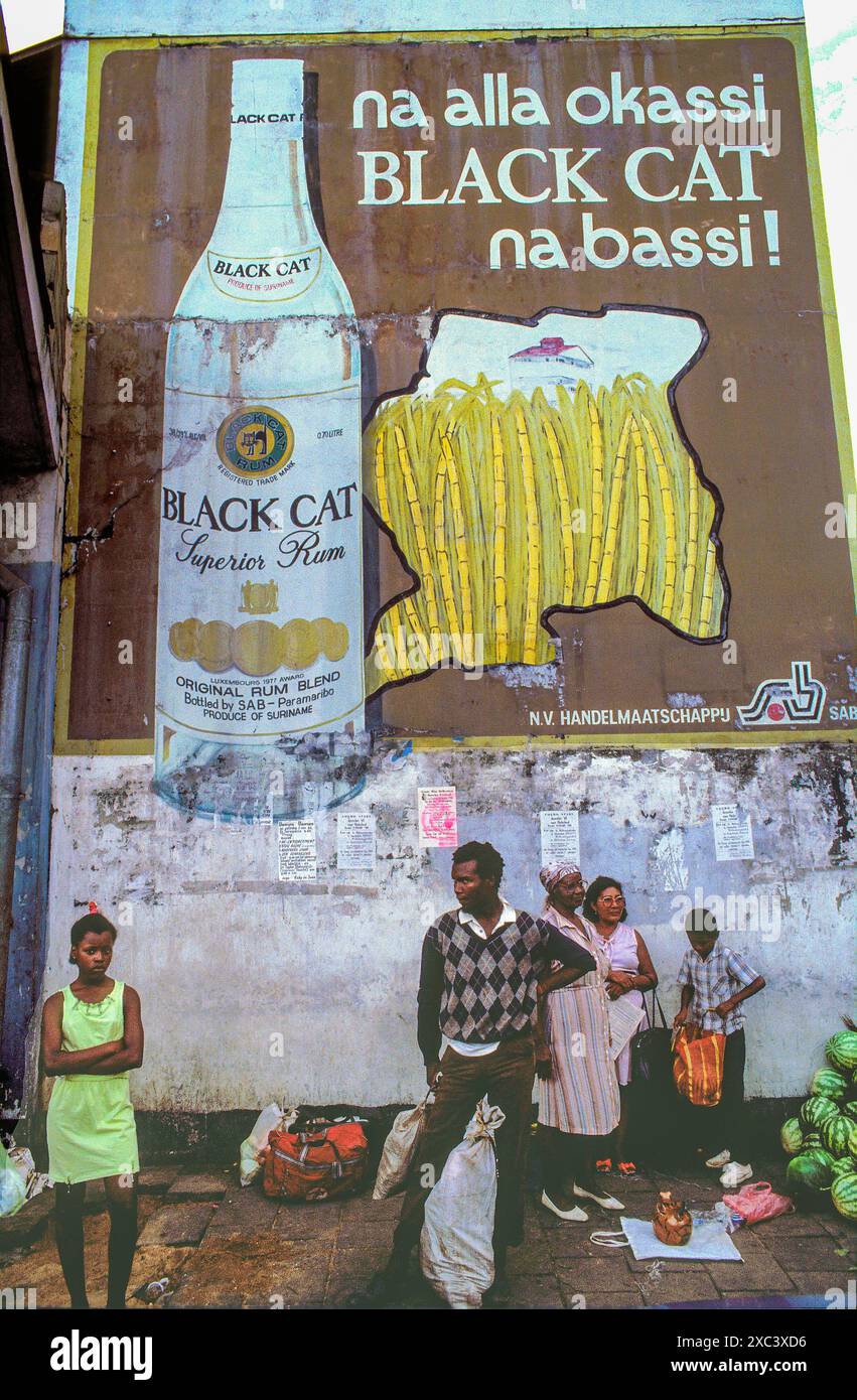 Suriname, Paramaribo. People waiting for a bus in front of billboard ...