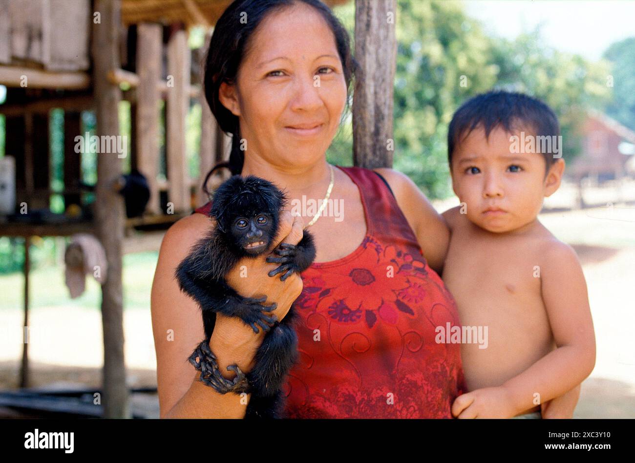 Suriname, Tepu. Portrait of a mother and child of the Trio tribe with a mantled howler Stock ...