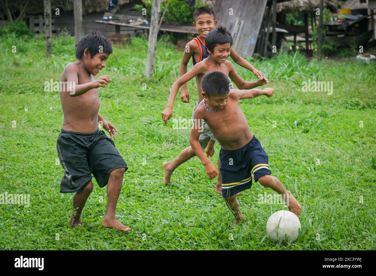 Suriname, boys of the Trio tribe play football on a field in front of their Amazon village Tepu ...