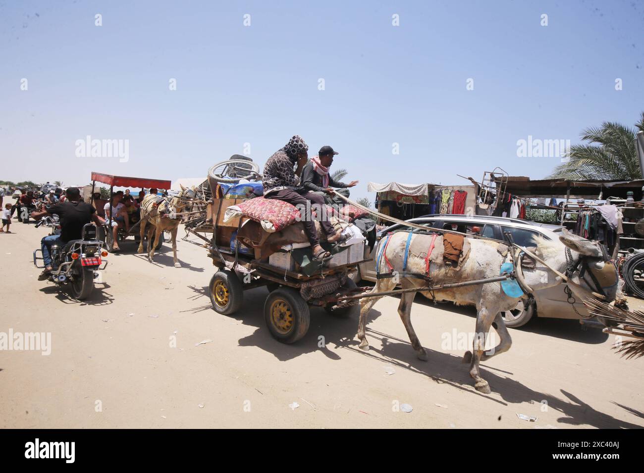 Men drive animal-drawn carts loaded with items past the tents and ...
