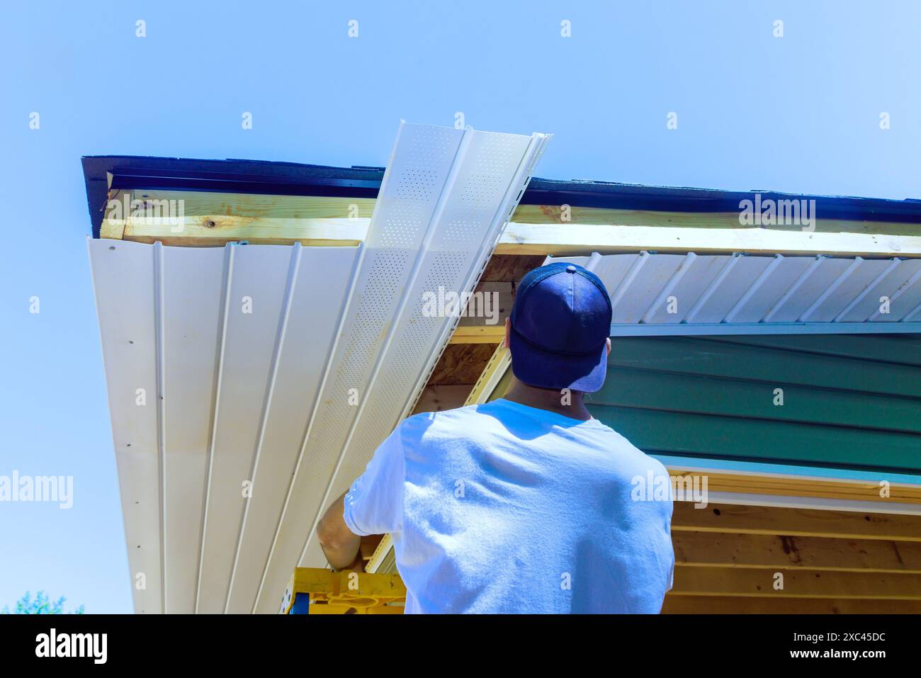 Mounting vinyl soffit plastic boards to roof rafters on ceiling house ...