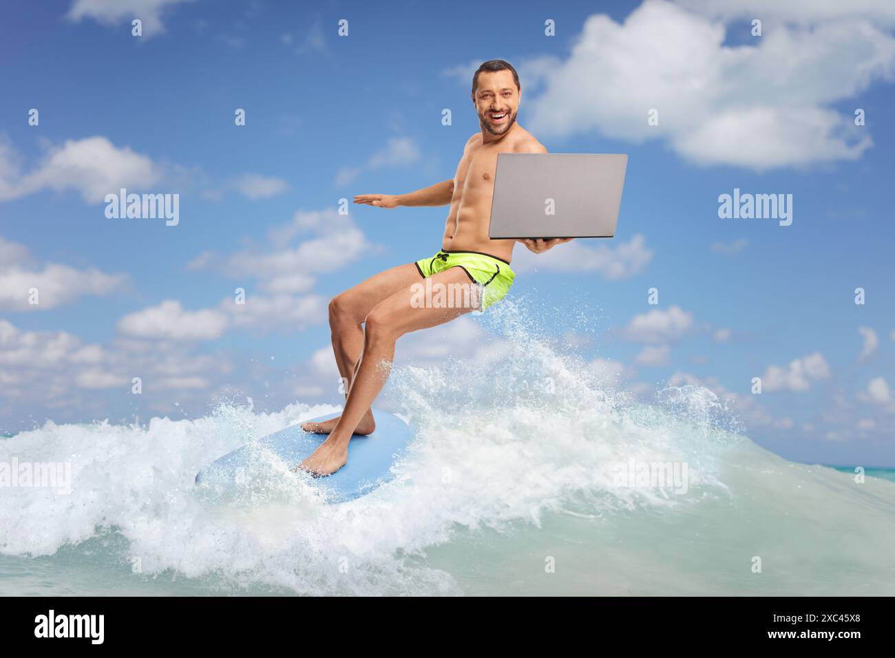 Man riding a surfboard in the sea and holding a laptop computer Stock ...