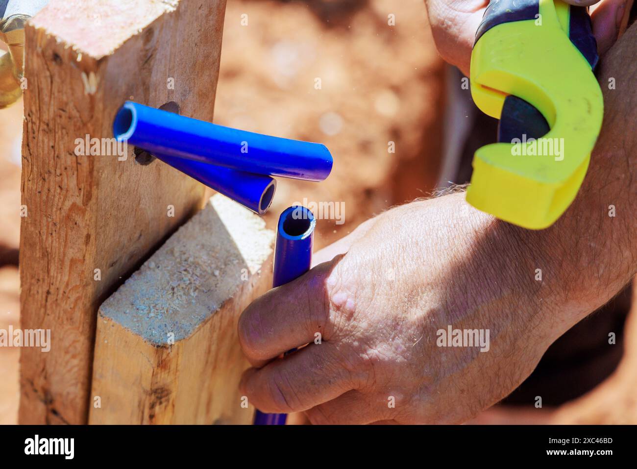 Plumber using saw tools to cut plastic blue PVC water piping system ...