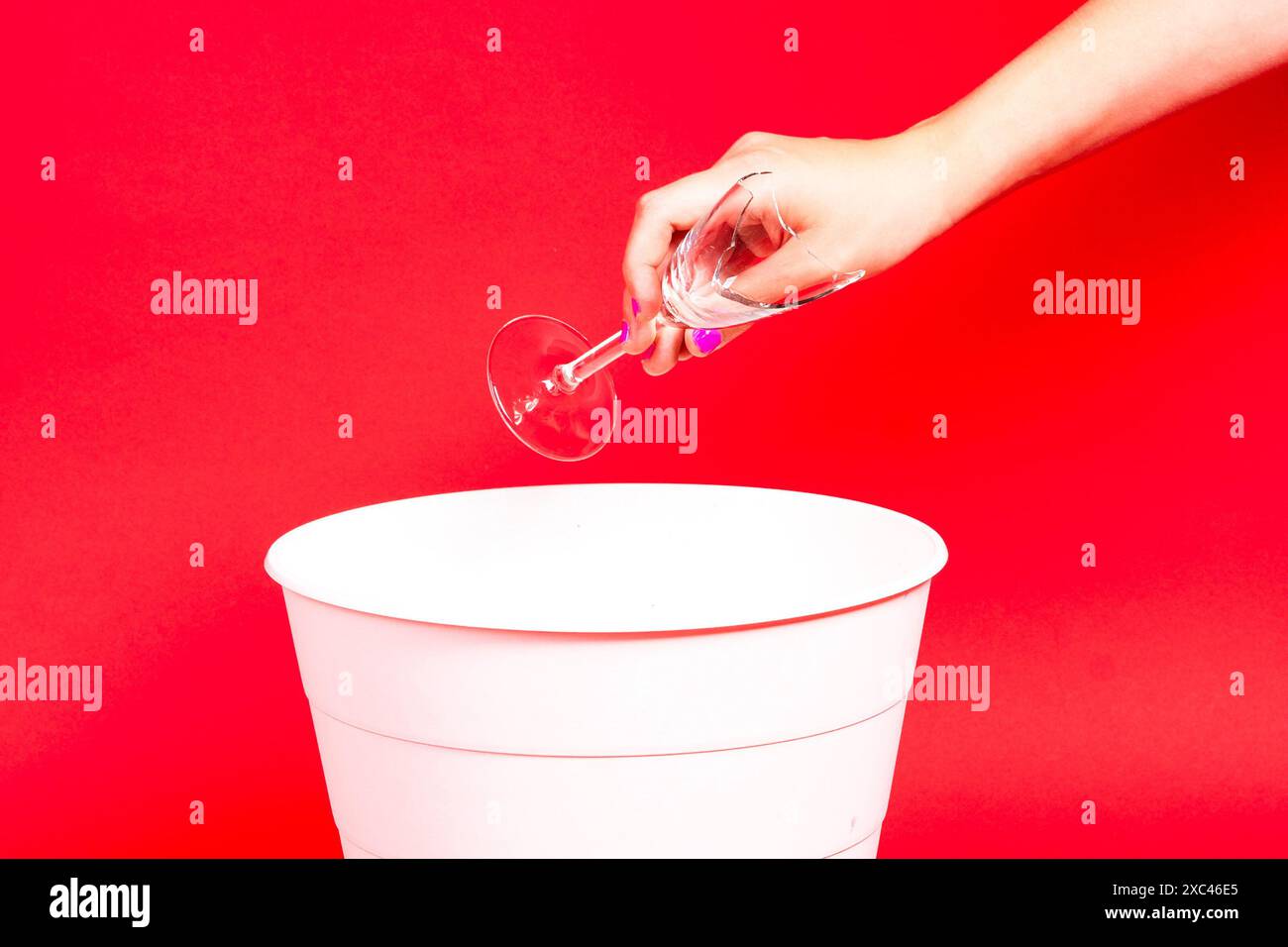 A woman throws a broken glass bowl into a glass collection bin, waste ...