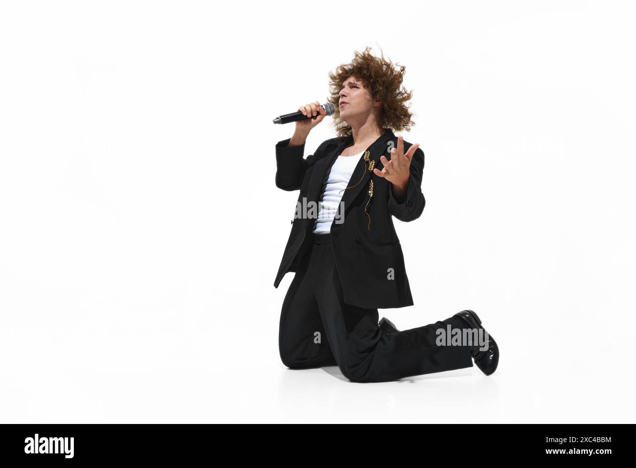 Spotlight Solo. Young man in black suit, energetic musician singing in ...