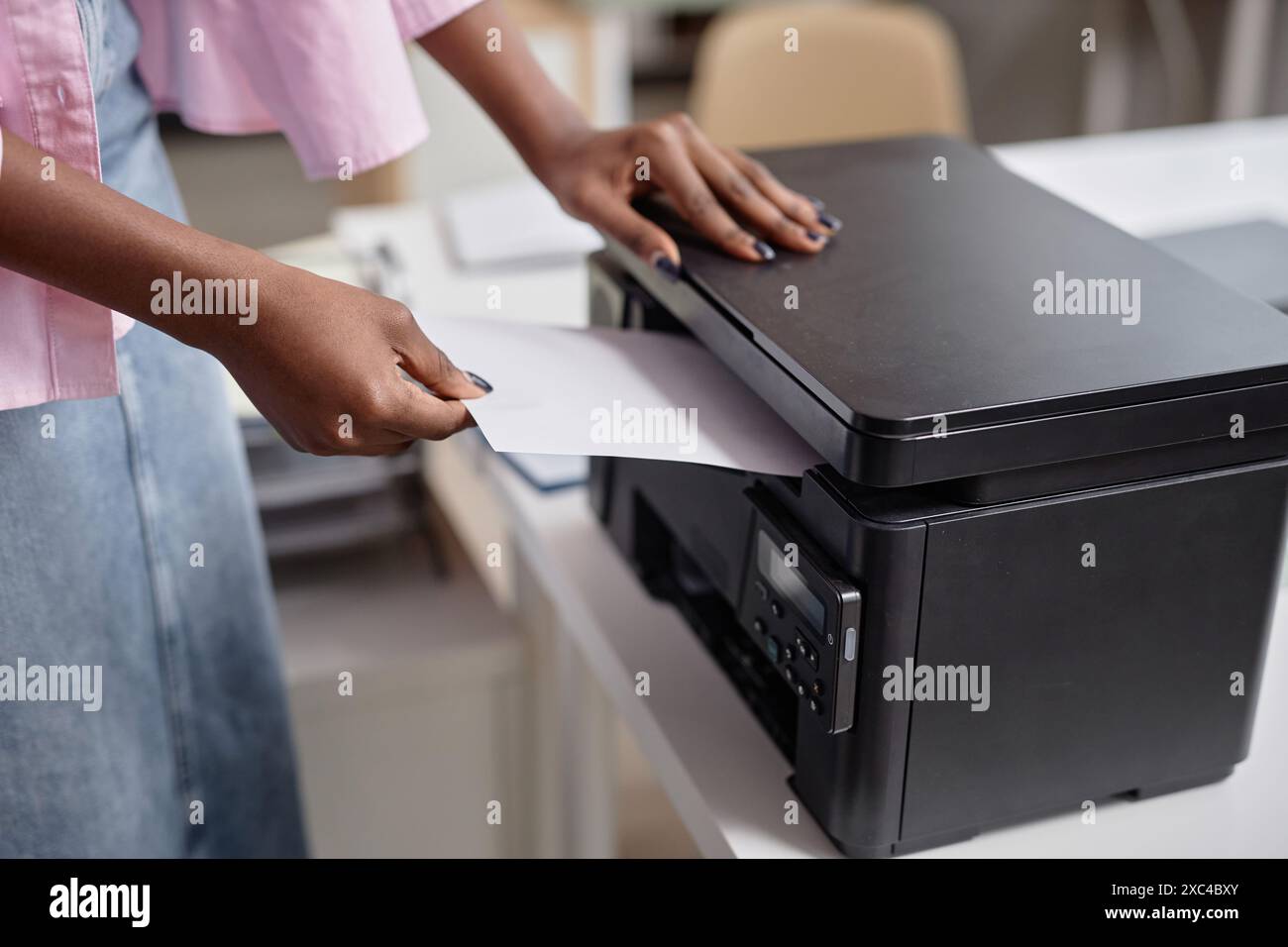 High angle close up of printer in office with female hands inserting ...