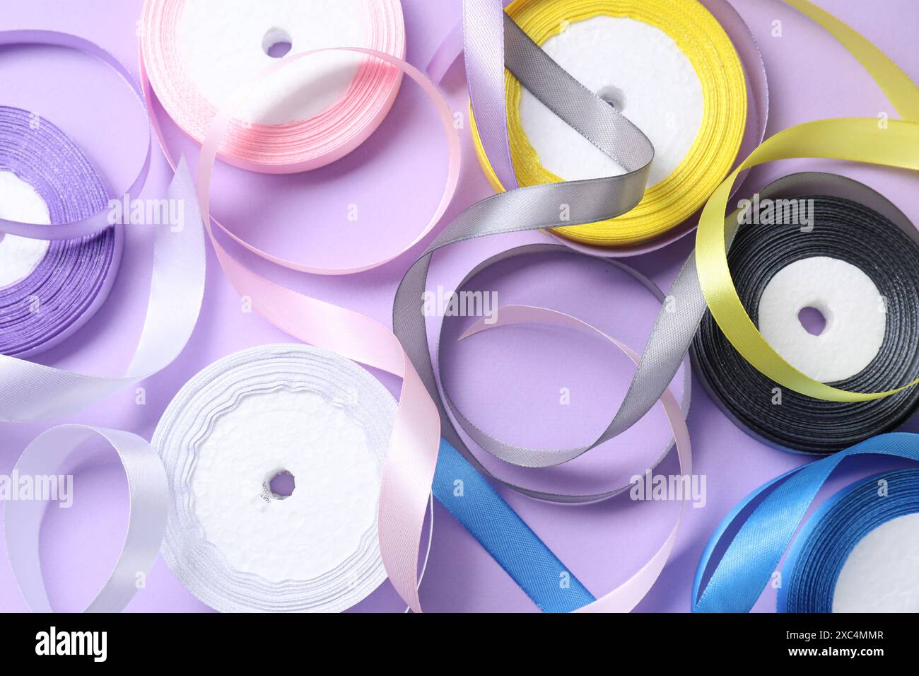 Ribbon reels in different colors on violet background, flat lay Stock ...