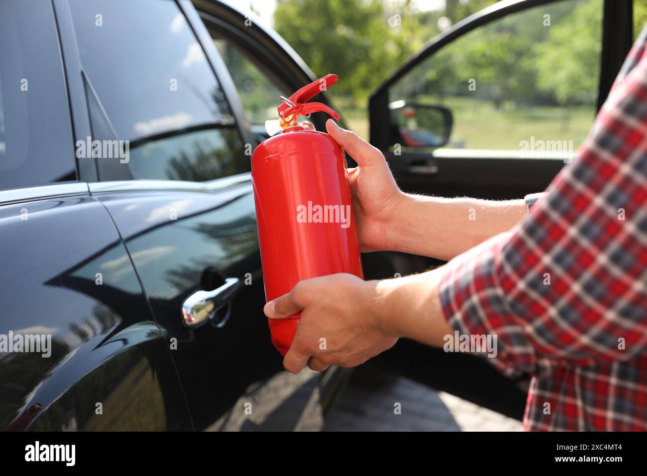 Man with fire extinguisher near car, closeup Stock Photo - Alamy