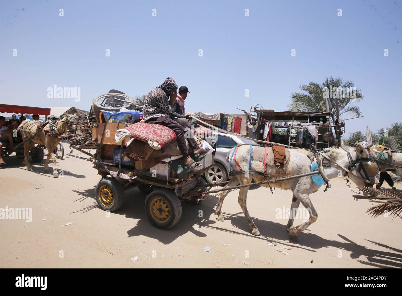 Men drive animal-drawn carts loaded with items past the tents and ...