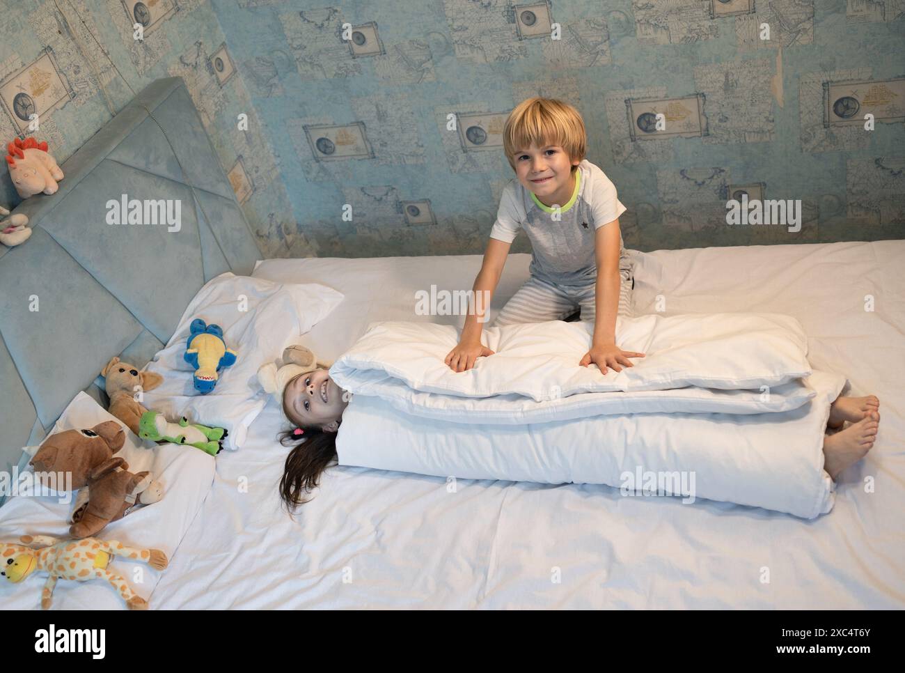 two children in pajamas, brother and sister, play with each other on a ...