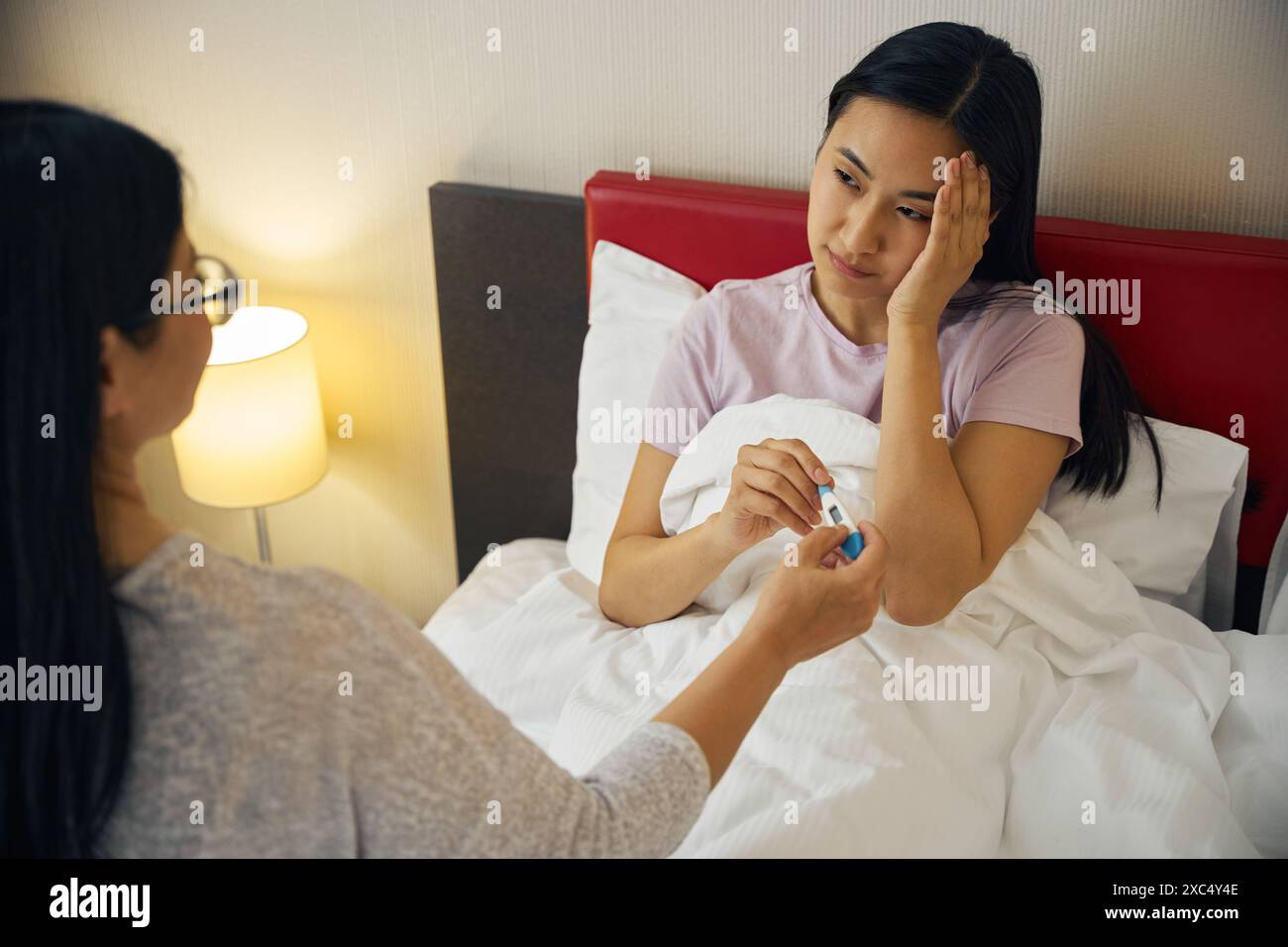Ill woman receiving temperature-measuring device from her parent in ...