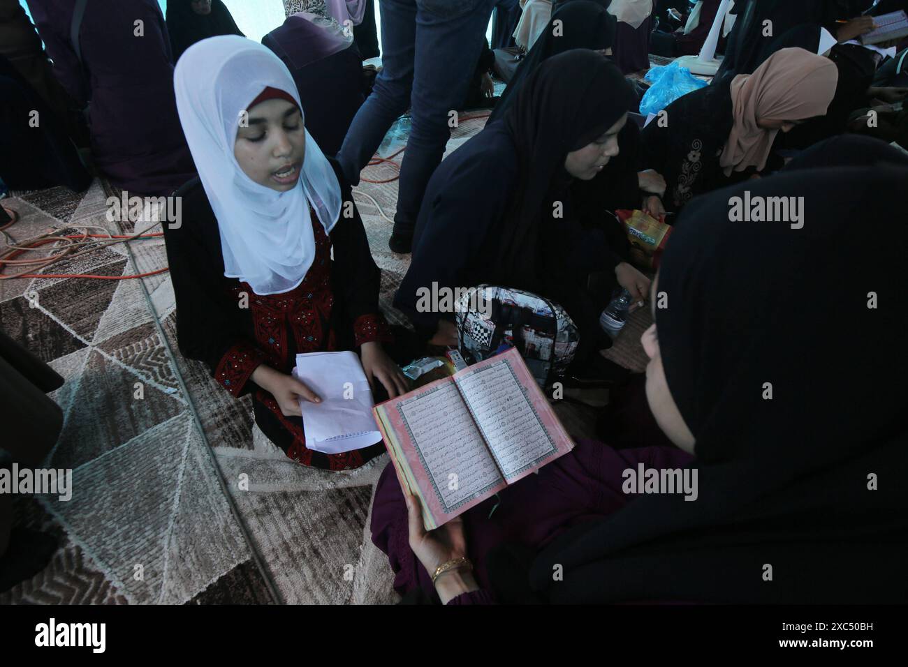 Women and girls assist each other to recite verses from the Koran ...