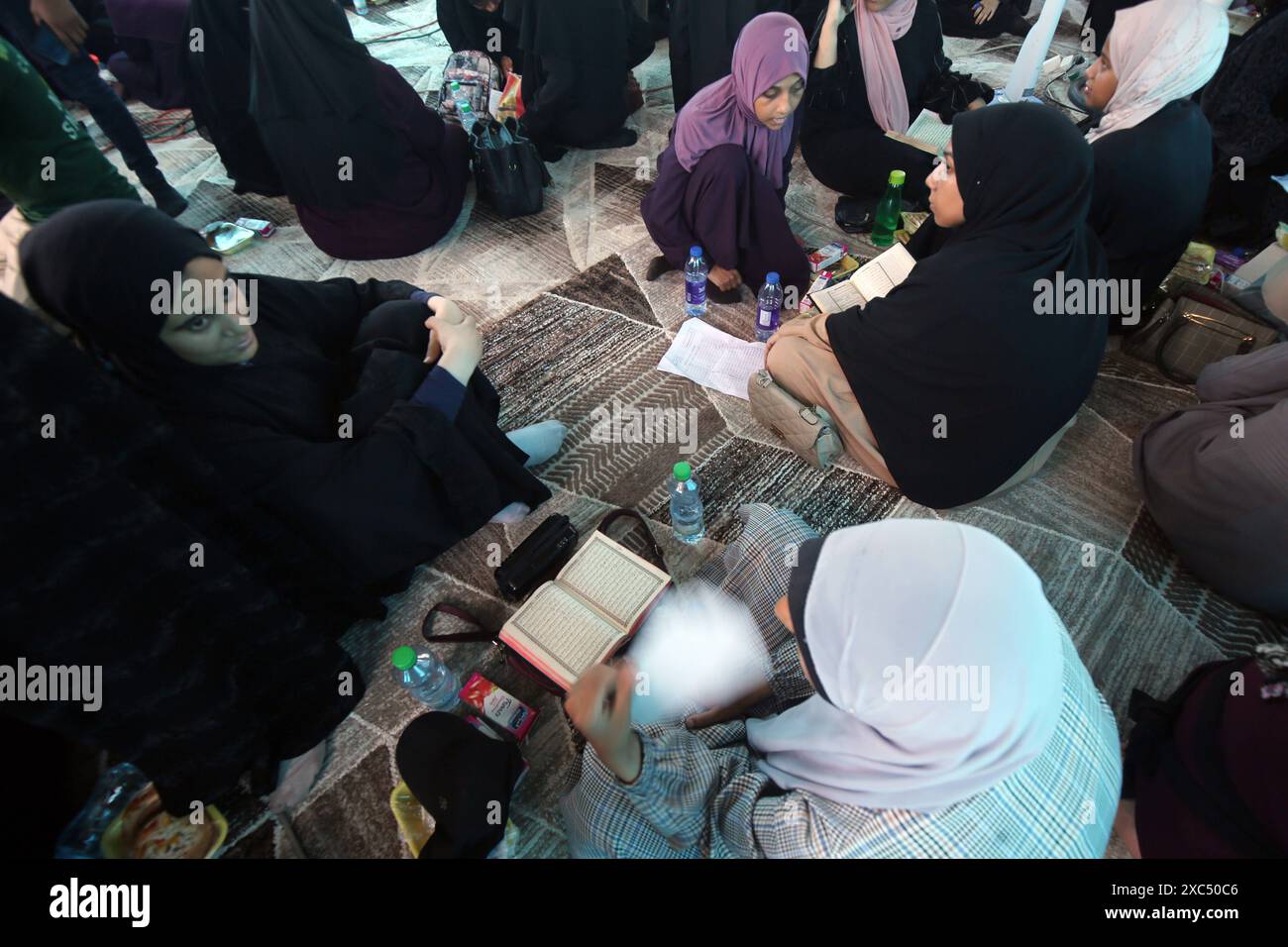 Women and girls assist each other to recite verses from the Koran ...
